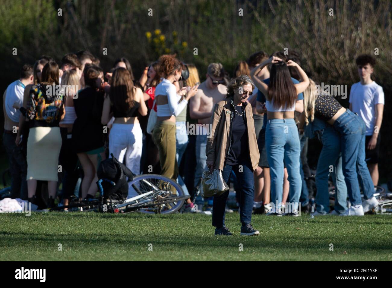 A woman walks past a gathering of youths on Lammas Land in Cambridge ...
