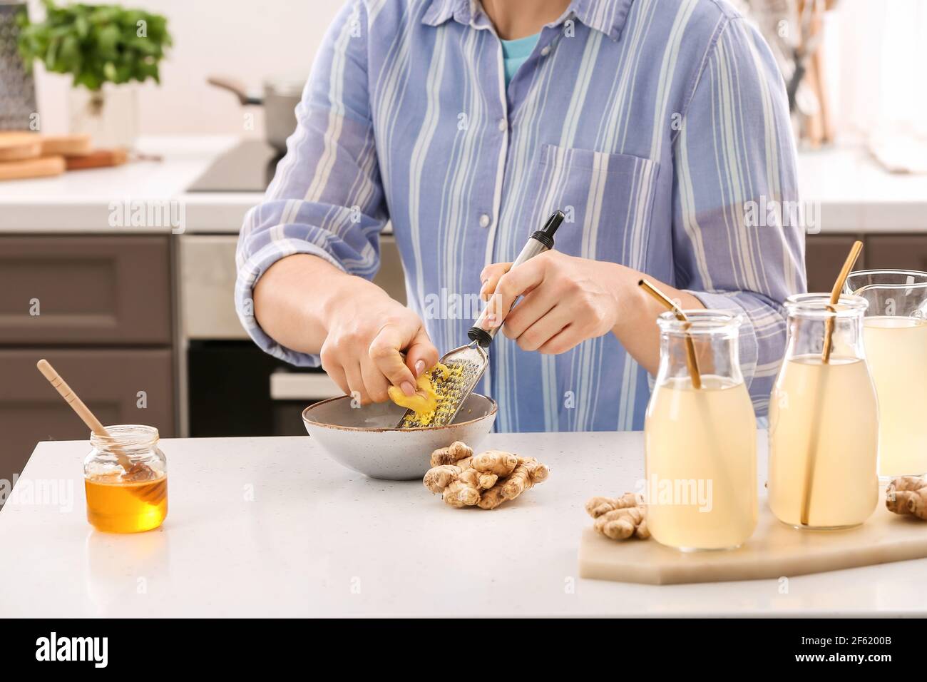 Woman grating ginger at table in kitchen Stock Photo - Alamy