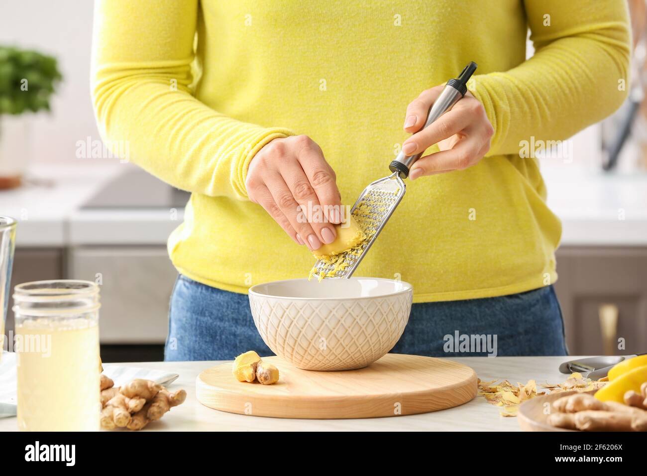 Woman grating ginger at table in kitchen Stock Photo - Alamy