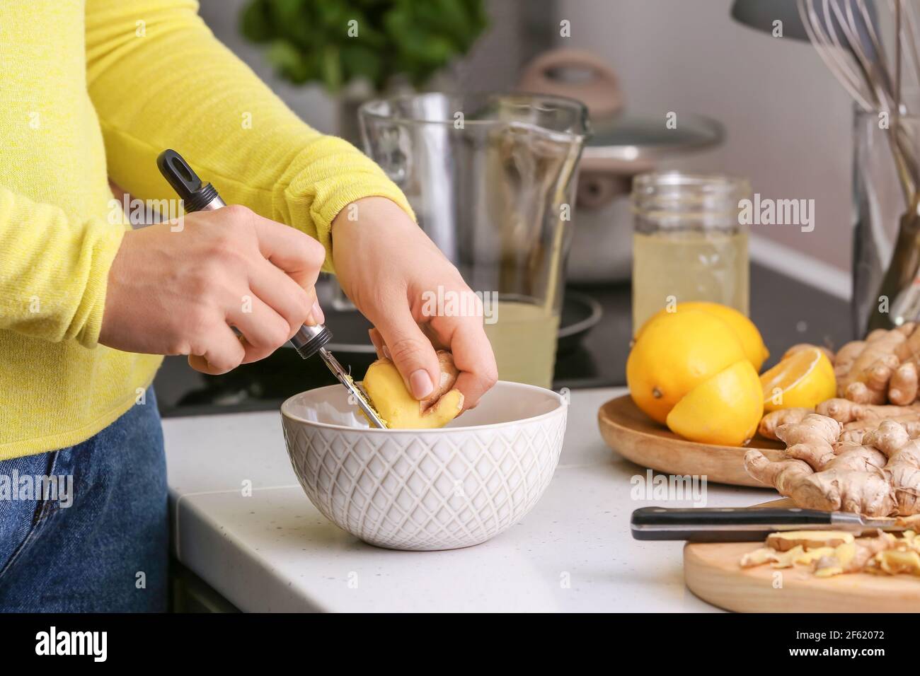 Woman grating ginger at table in kitchen Stock Photo - Alamy