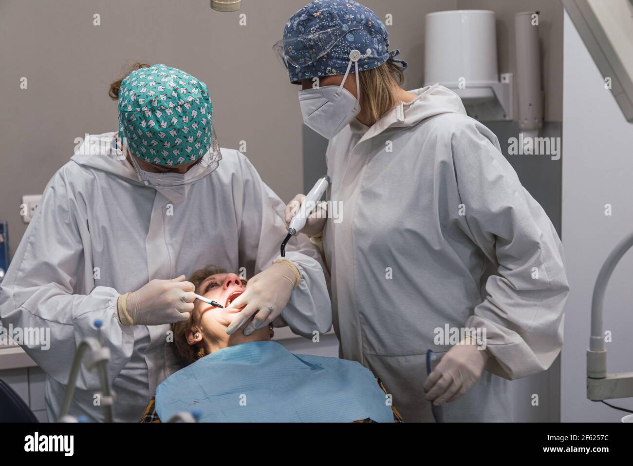 Two female dentists working with their patient's open mouth. Dentist and nurse is examining ...