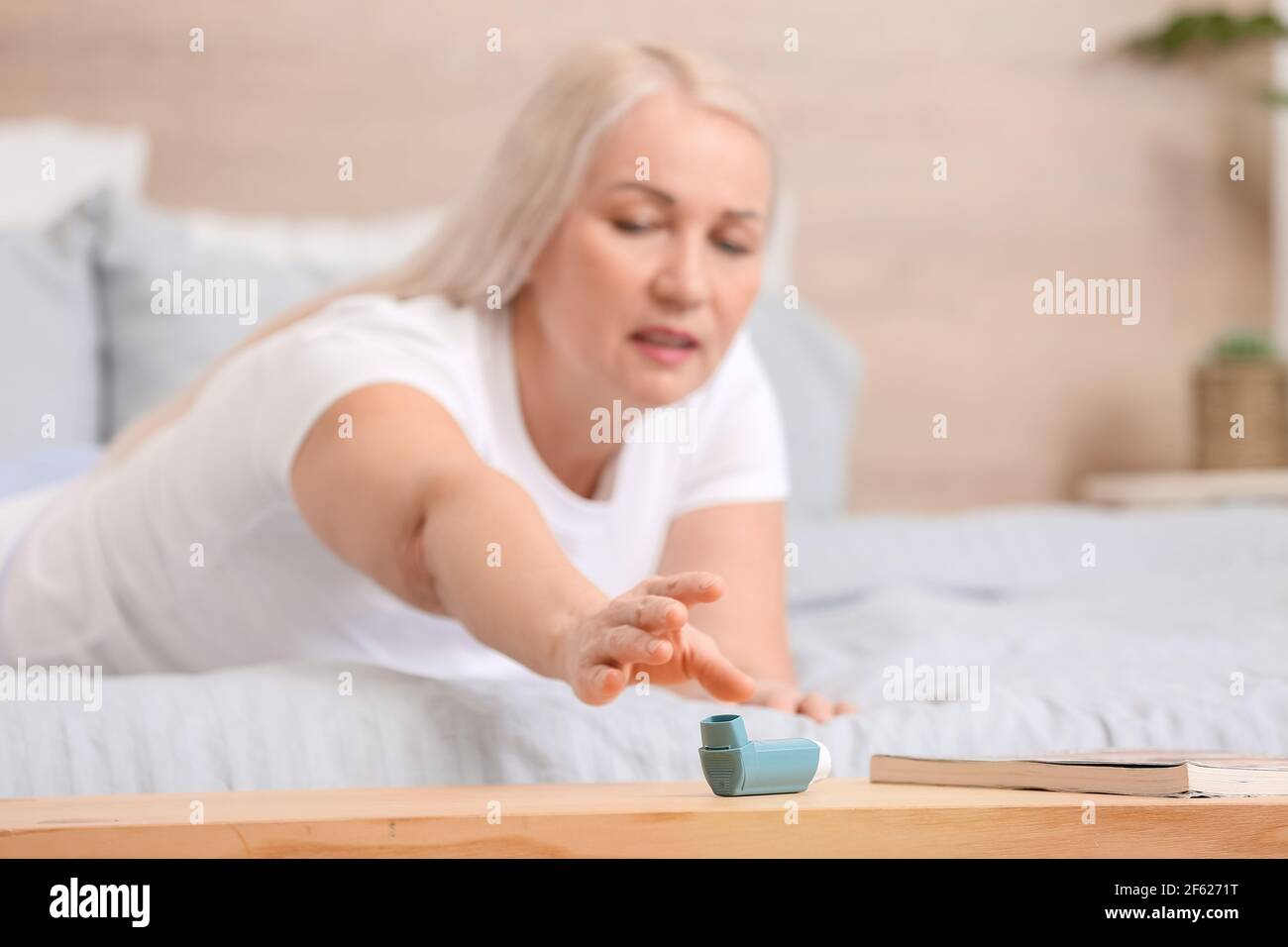 Mature woman taking inhaler from table Stock Photo - Alamy