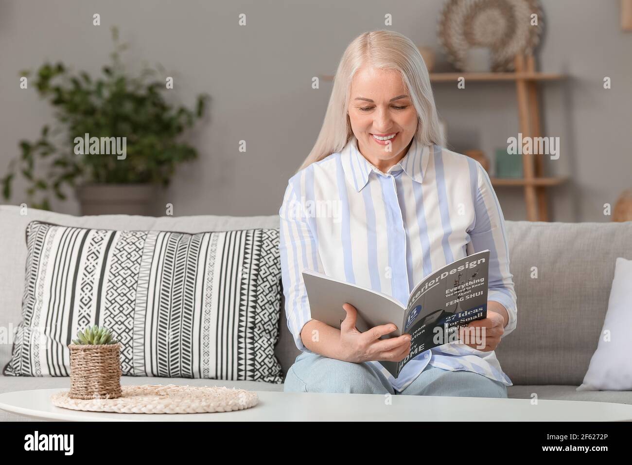 Happy mature woman reading magazine at home Stock Photo - Alamy