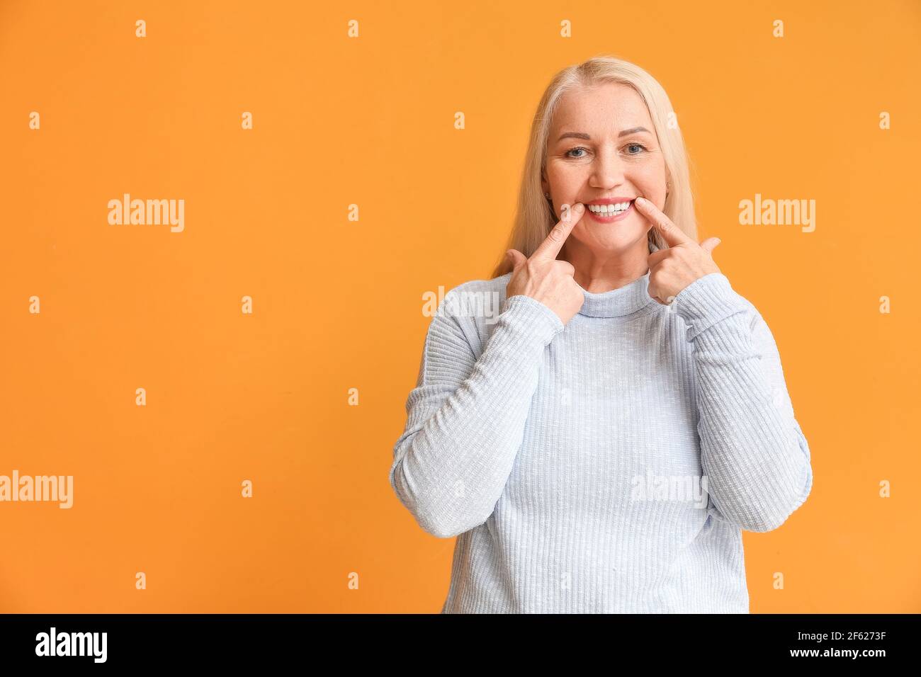 Happy mature woman with beautiful smile on color background Stock Photo - Alamy