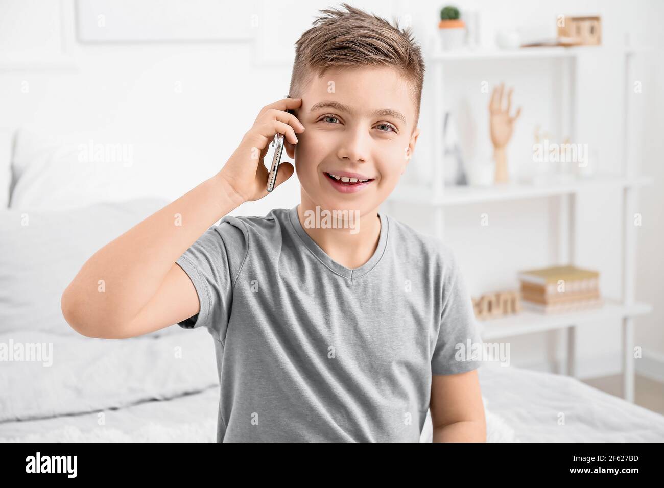 Happy little boy talking by mobile phone at home Stock Photo - Alamy