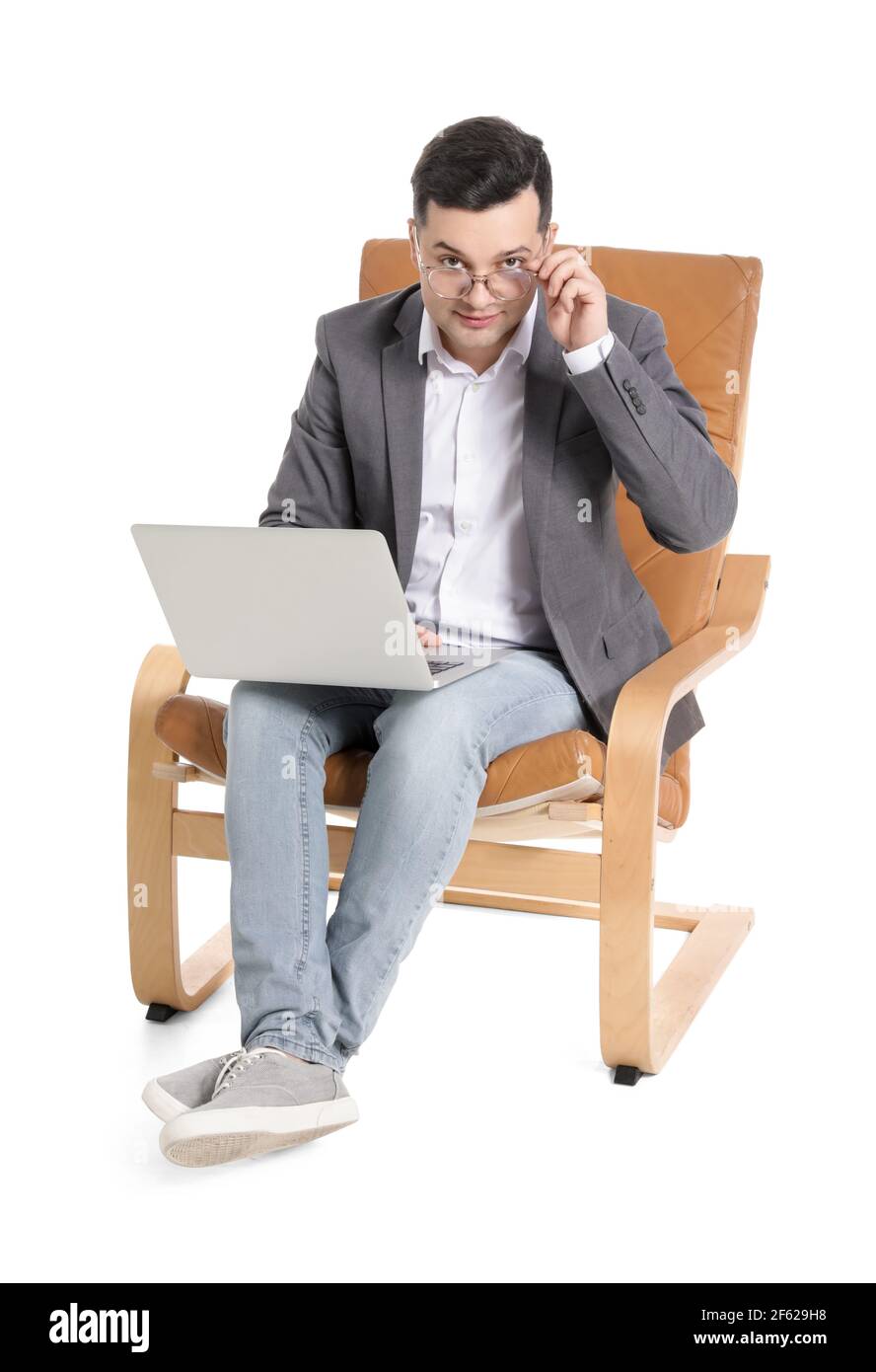 Young man with laptop sitting in armchair on white background Stock ...