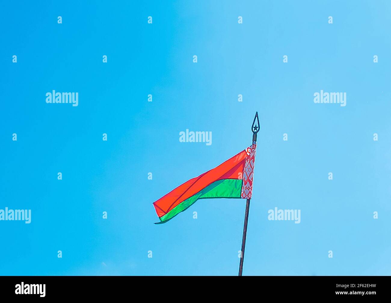 Belarusian national flag on a background of bright daytime blue sky ...