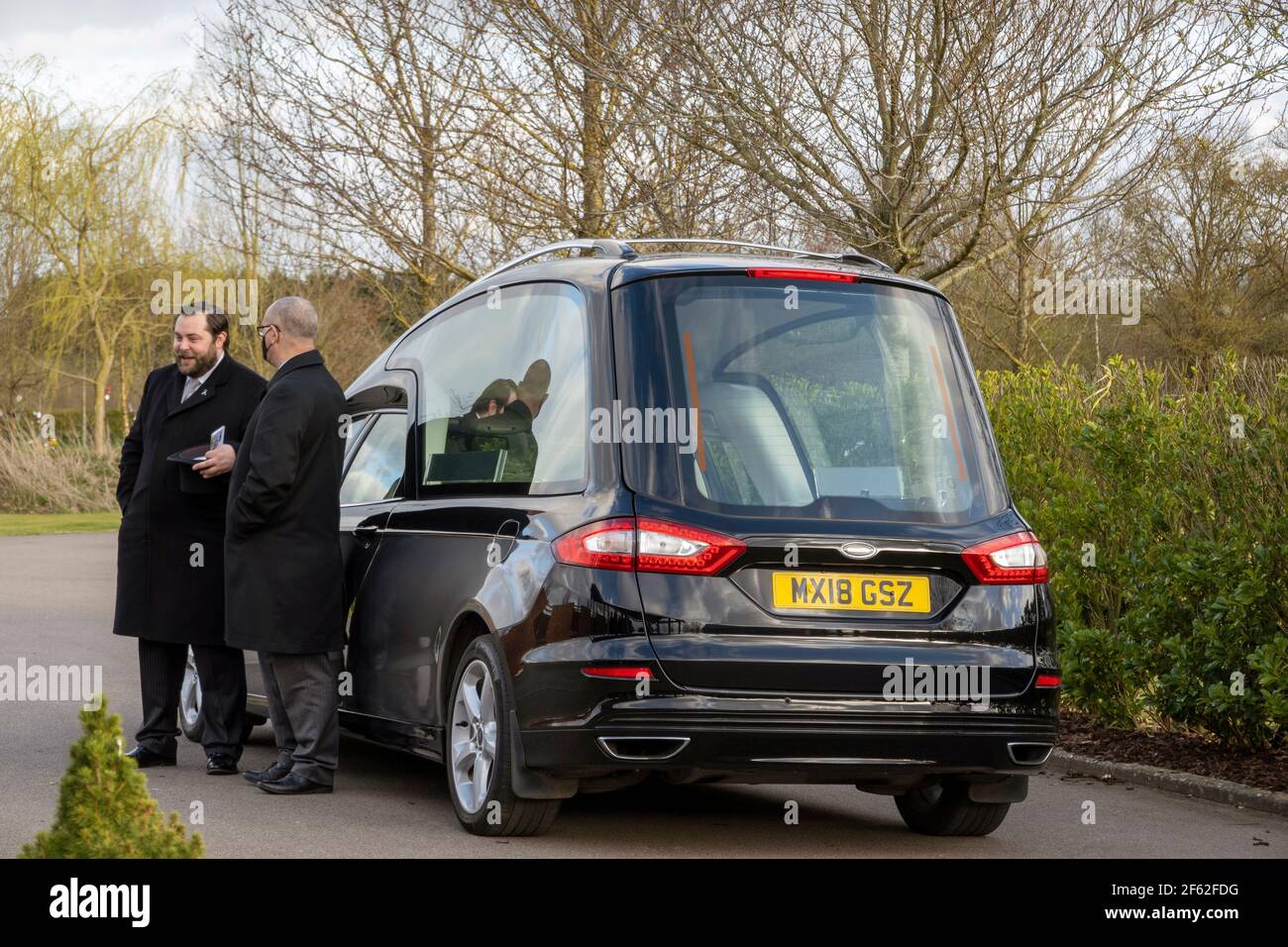 England, UK. 2021. A large modern black hearse with funeral director ...