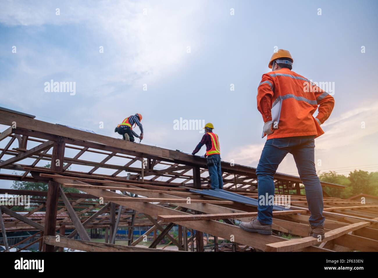 Engineer technician watching team of roofer working on roof structure ...