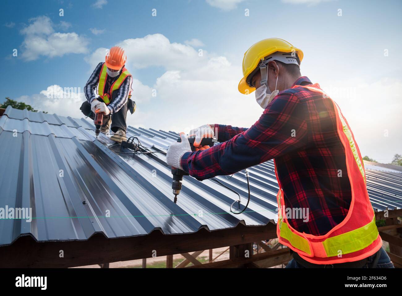 Two Roofer worker safety wear using air or pneumatic nail gun and ...