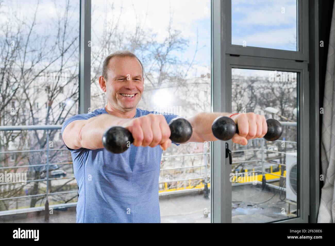 Smiling middle age fit sportsman exercise at light gym with panoramic ...
