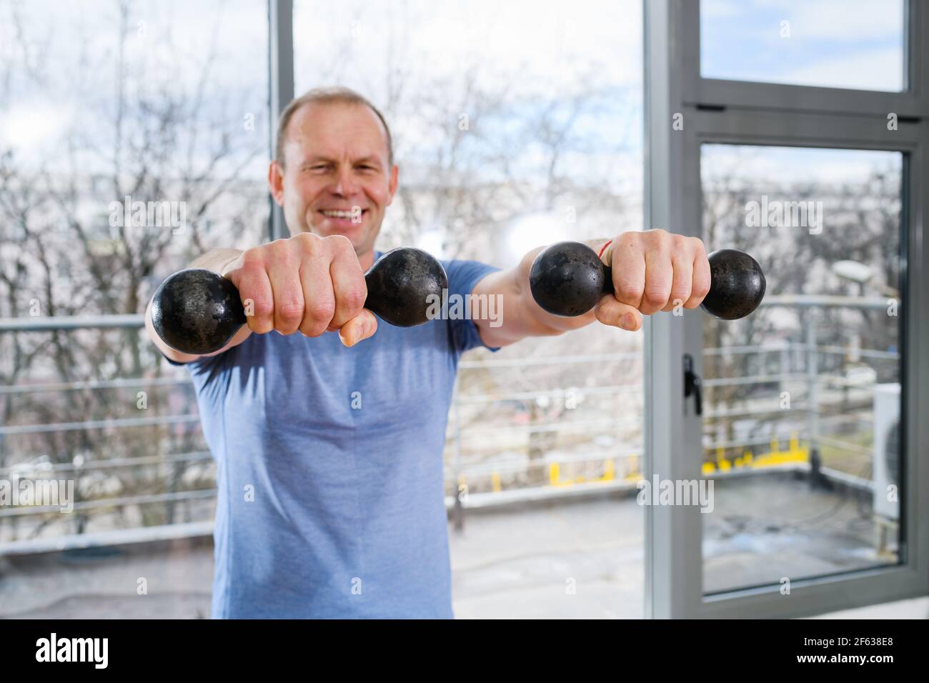 Smiling middle age fit sportsman exercise at light gym with panoramic ...