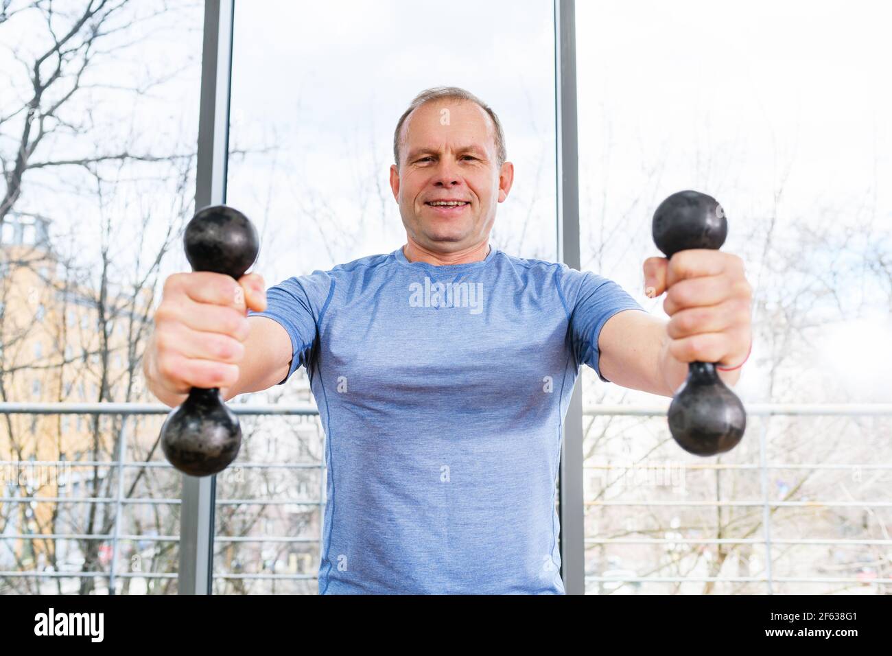 Smiling middle age fit sportsman exercise at light gym with panoramic ...
