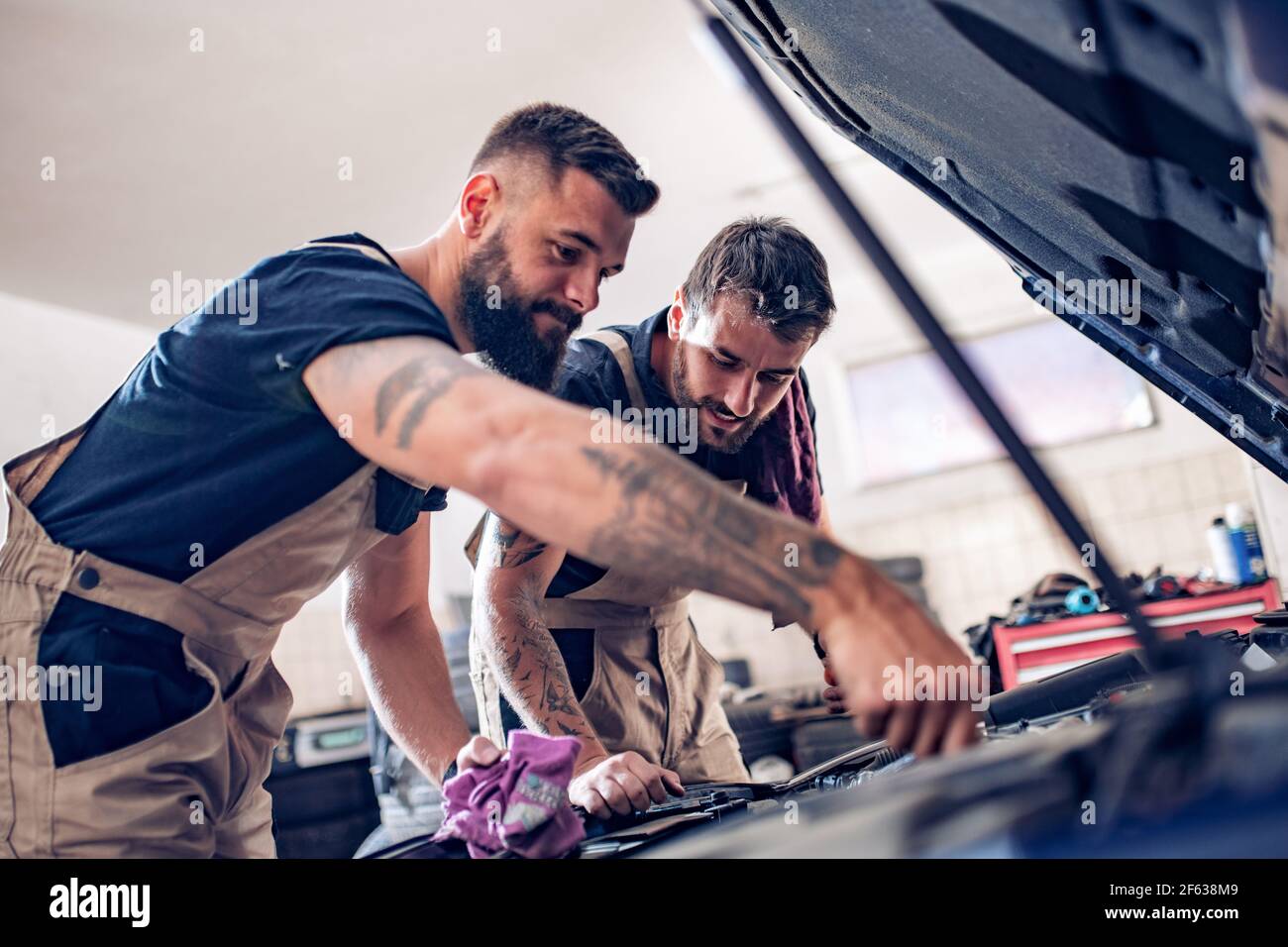 Auto mechanics check the oil in the engine,close up.Teamwork concept ...