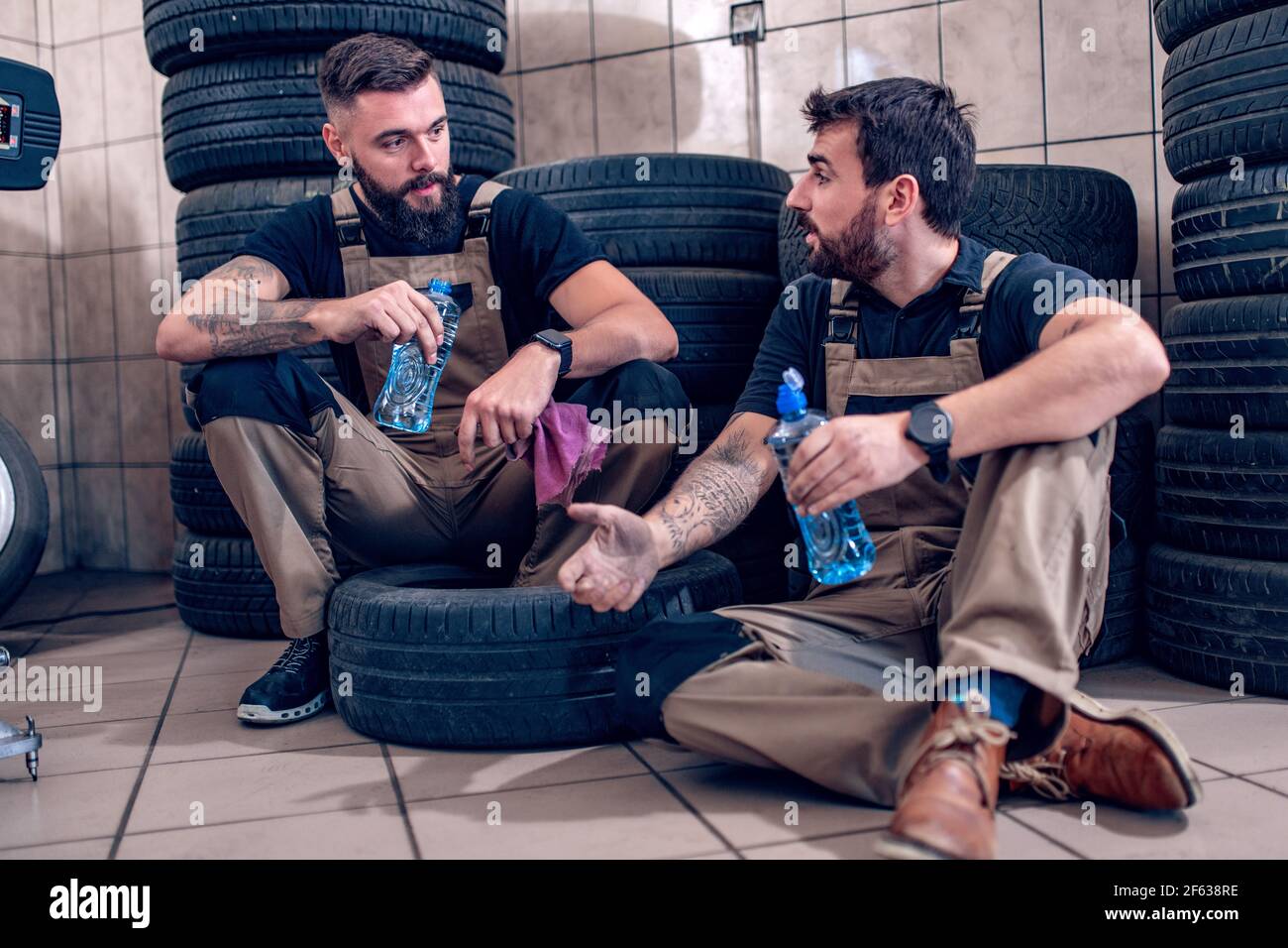 Mechanics resting after hard work, they changing tires on their job ...