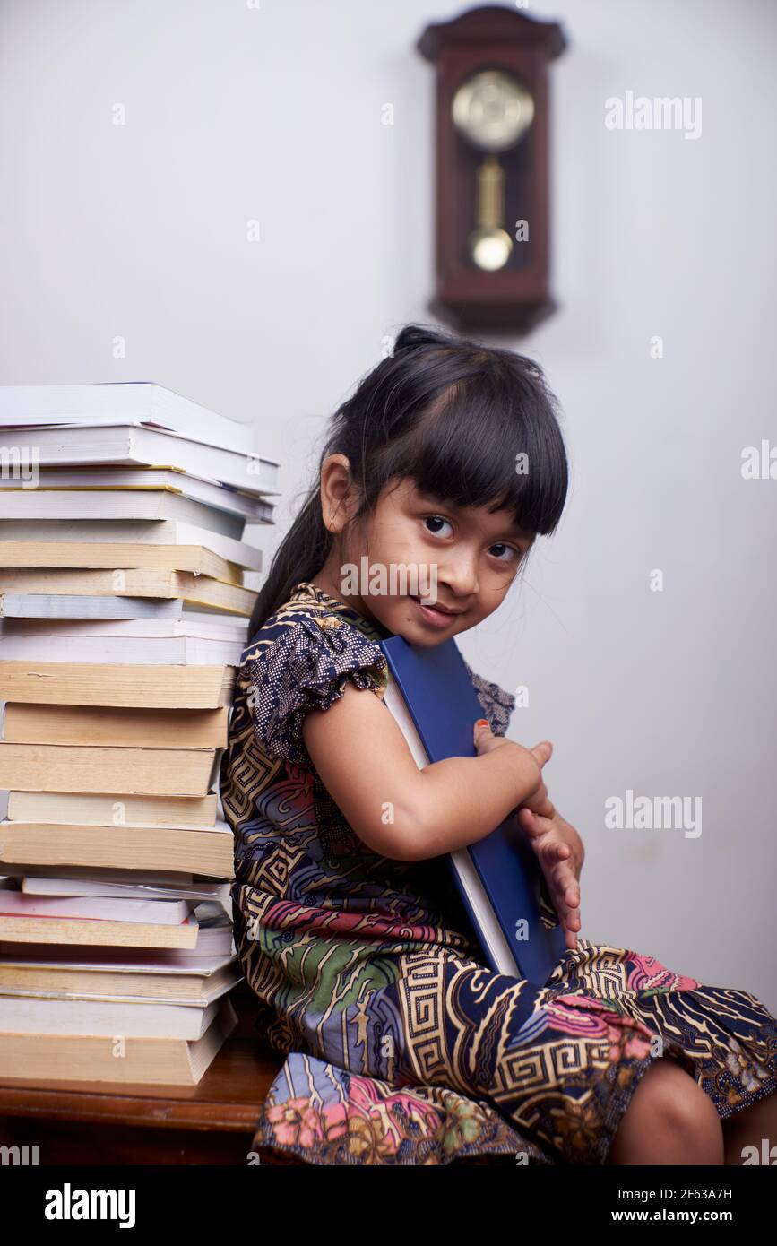 Portrait of cute little girl reading book and study at home schooling ...