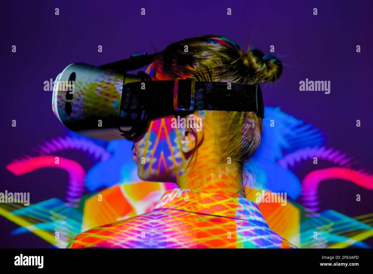 Back view: woman using virtual reality headset at dark interactive VR ...