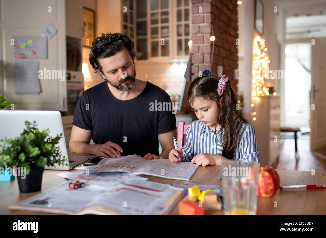 Father with small daughter in kitchen, distance learning, home office ...