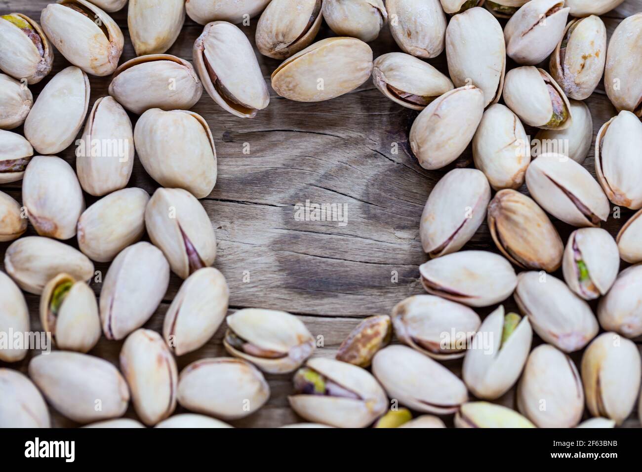 Lots of pistachios in their shell on a wooden chopping board. Natural ...