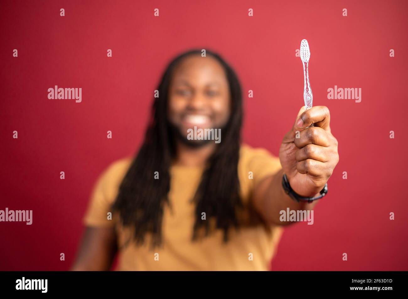 Selective focus at the toothbrush in hand of smiling man. Happy African ...