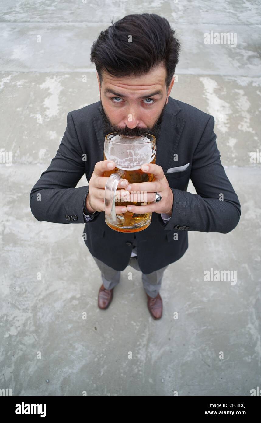 Full length, wide angle. Funny man in classic suit drinking beer ...