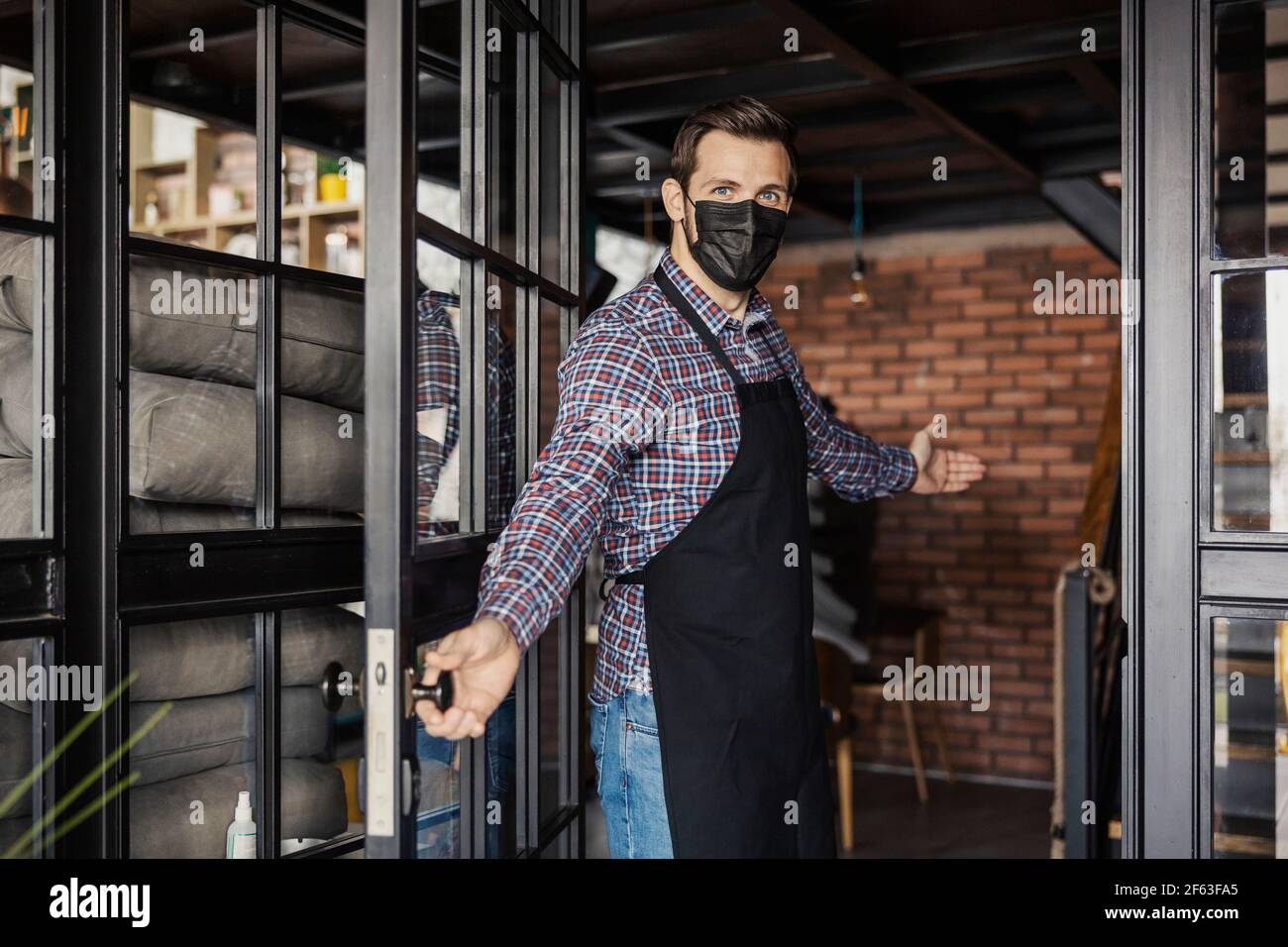 Welcome to the restaurant, we are open. A male waiter in a plaid shirt ...