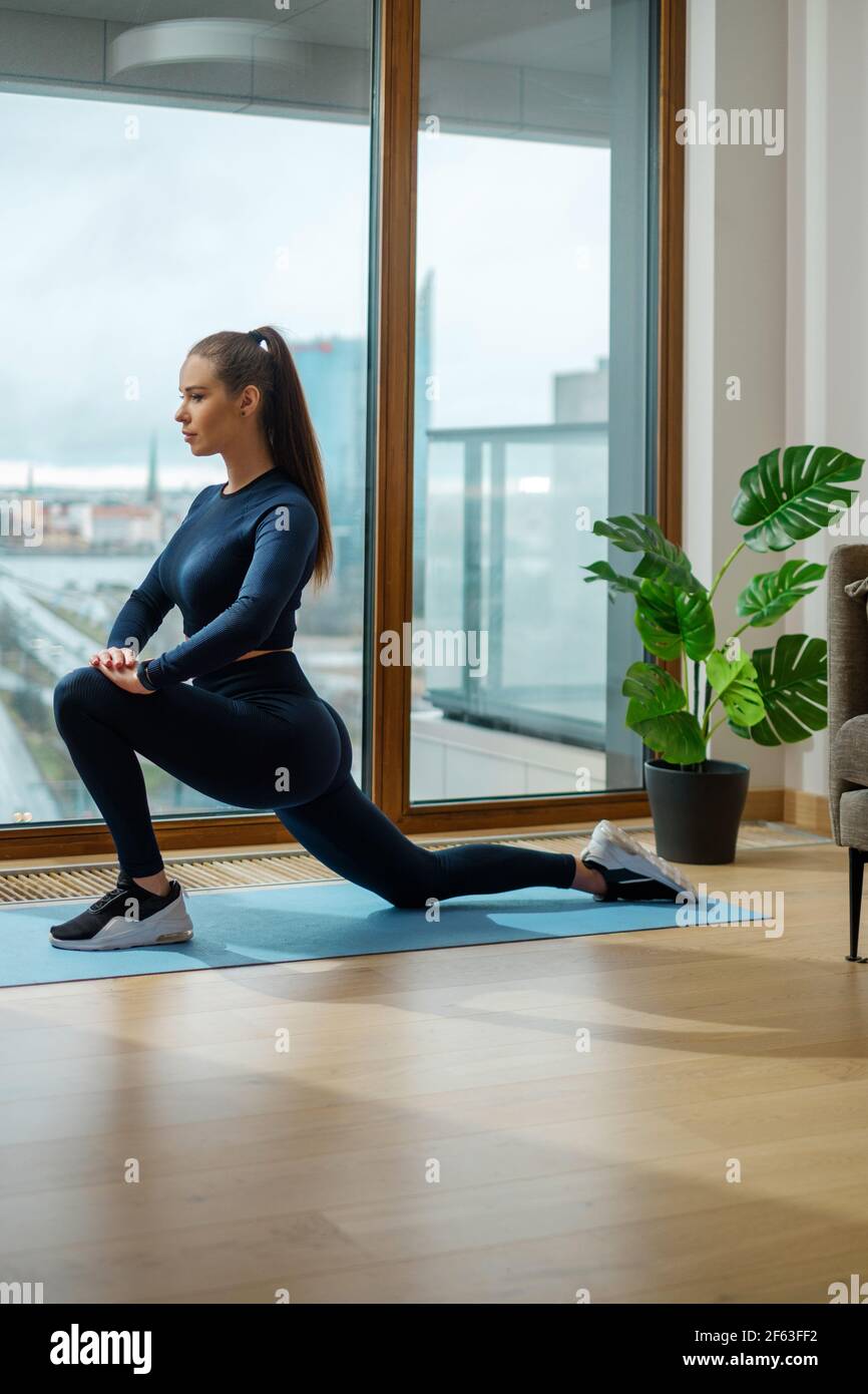 Woman practices yoga in warrior position on glazed balcony Stock Photo ...
