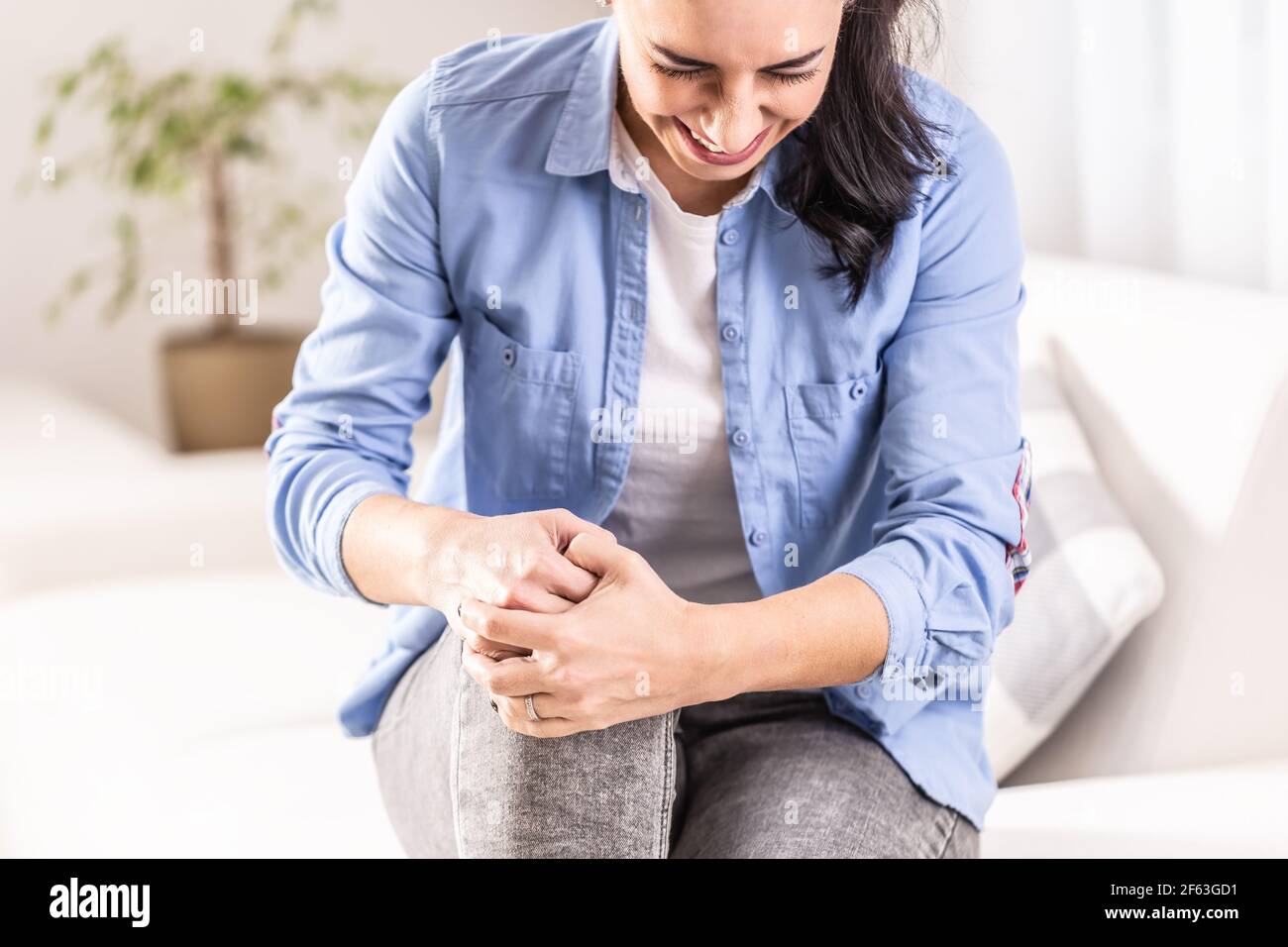 Girl in pain of a knee holding it by both hands with painful facial ...