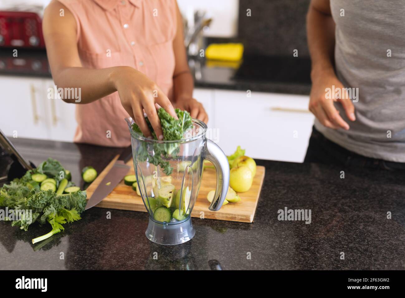 Diverse couple in kitchen making health drink Stock Photo - Alamy