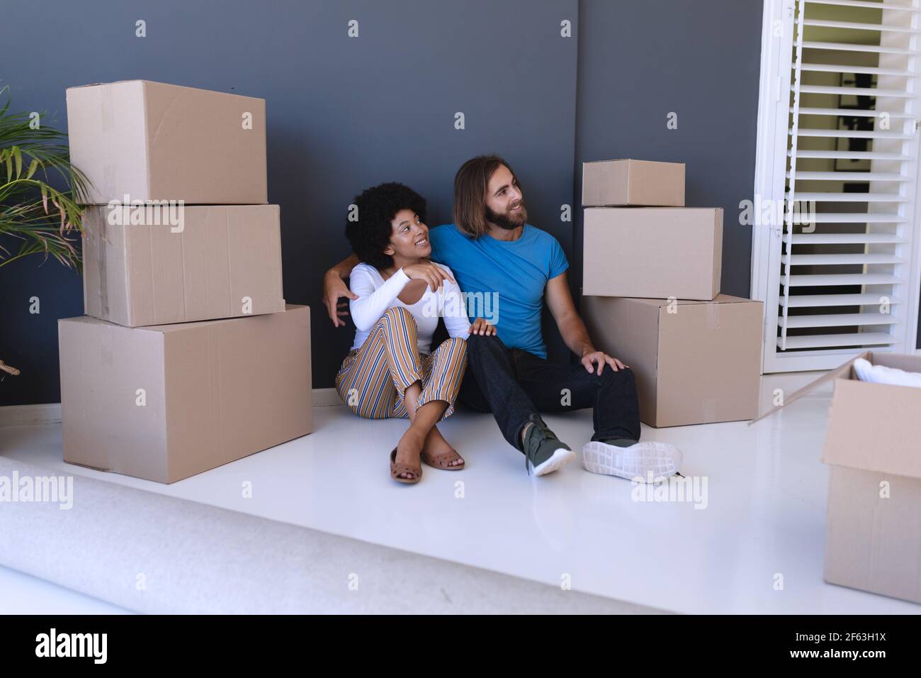 Happy diverse couple moving house sitting and embracing Stock Photo - Alamy