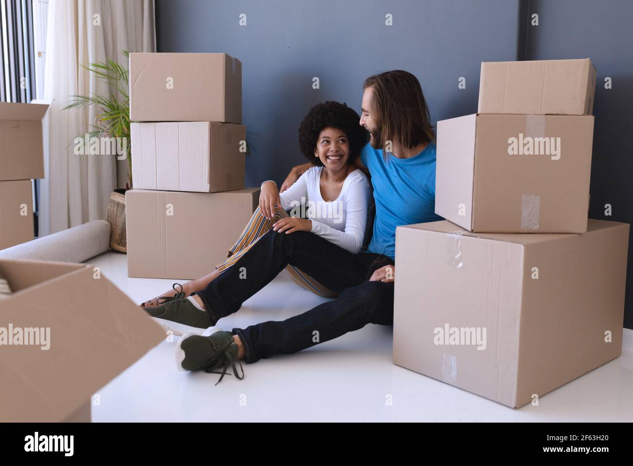 Happy diverse couple moving house sitting and embracing Stock Photo - Alamy