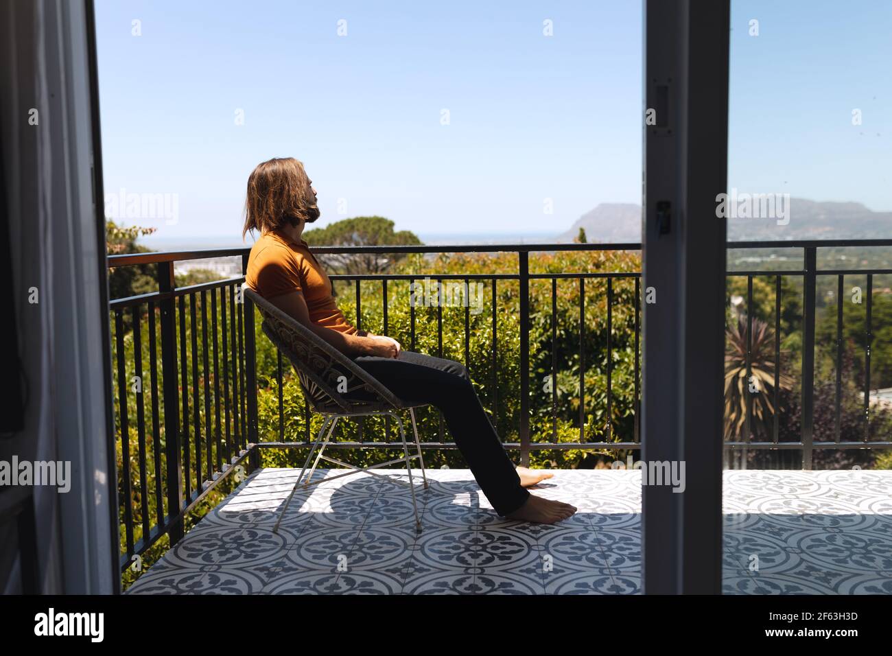 Caucasian man sitting on balcony looking away Stock Photo - Alamy