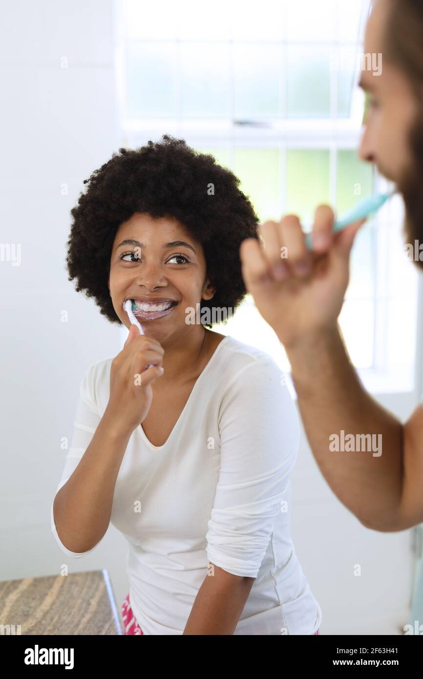 Diverse couple standing in bathroom brushing teeth Stock Photo - Alamy