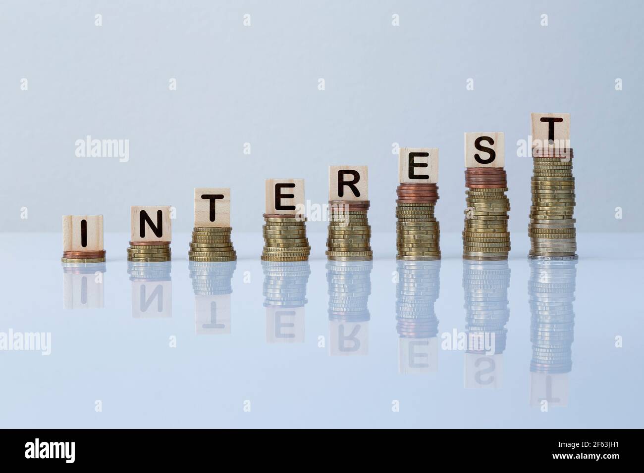 Word "INTEREST" on wooden blocks on top of ascending stacks of coins ...