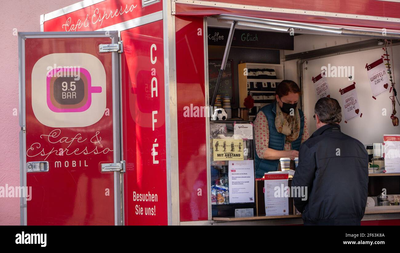 Mobile cafe coffee maker wearing mask sells coffee to a client. Red ...