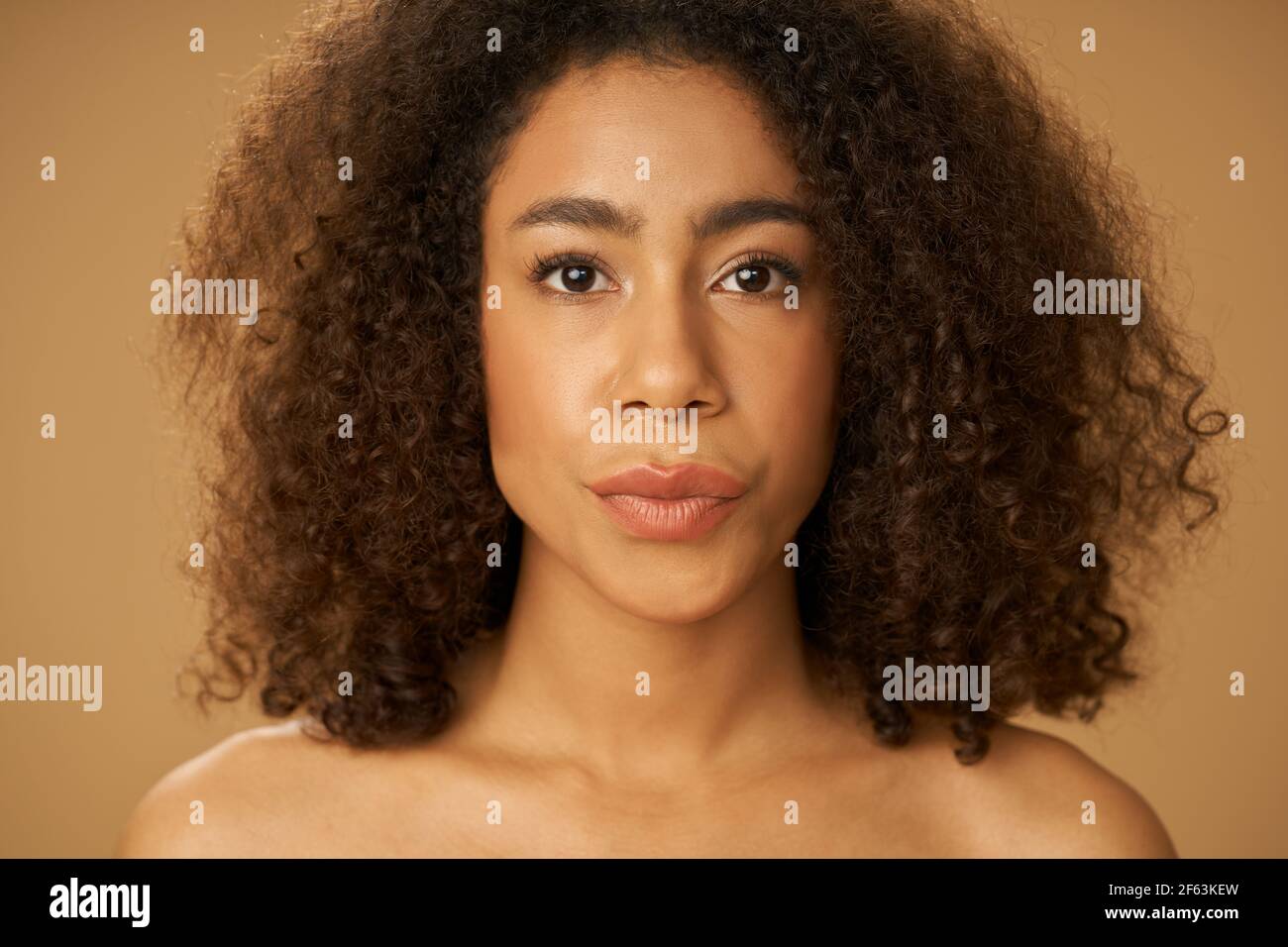 Portrait of mixed race young woman with curly hair posing isolated over ...