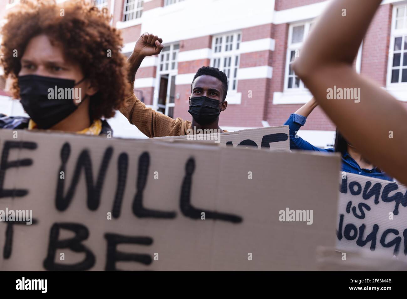 Diverse male and female protesters on march in face masks holding ...