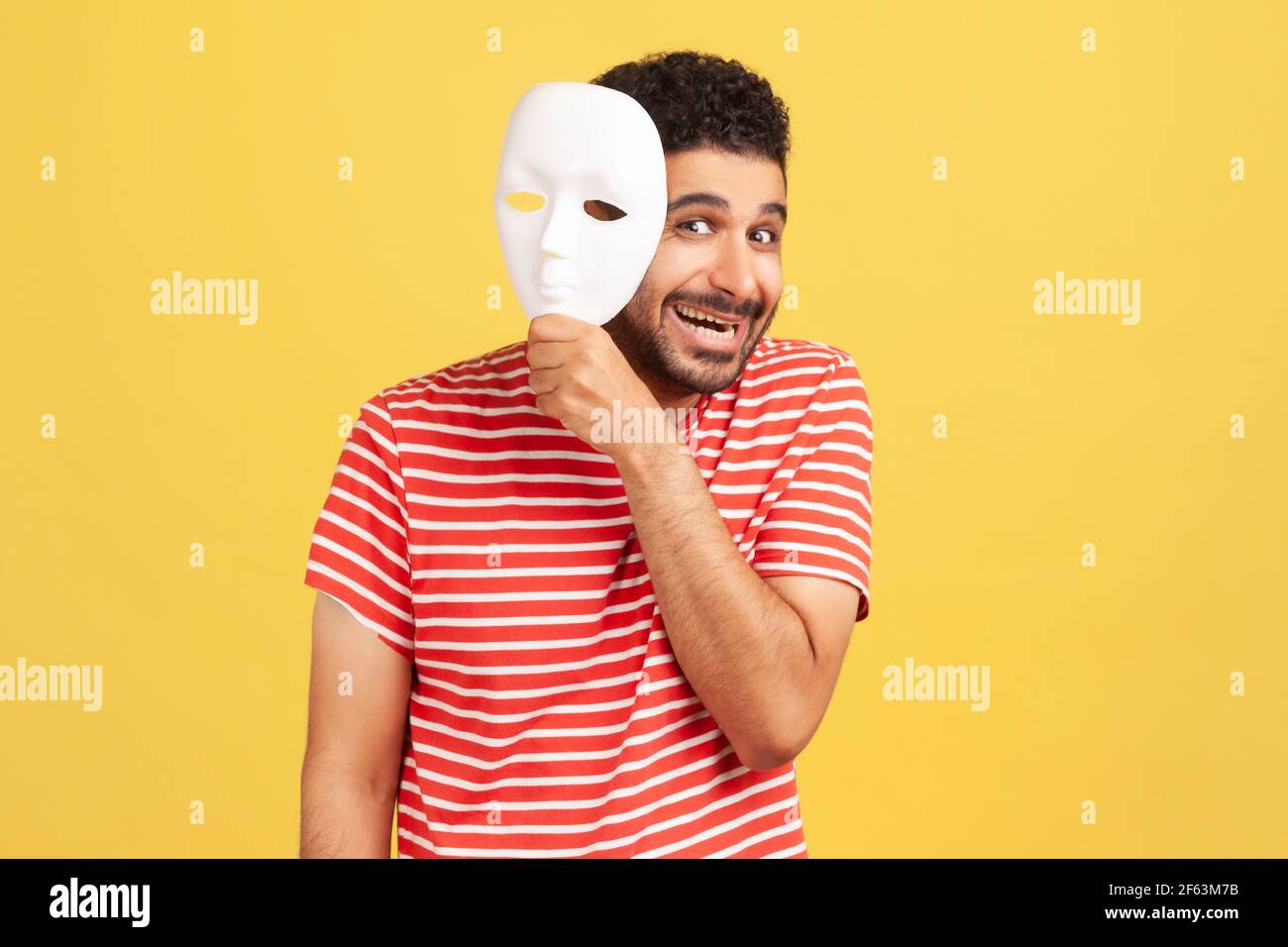 Happy bearded man removing white mask from face showing his smiling ...