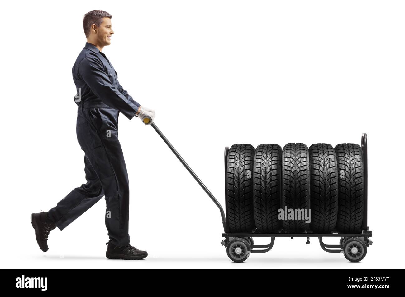 Worker in a uniform pushing vehicle tires on a hand truck isolated on ...