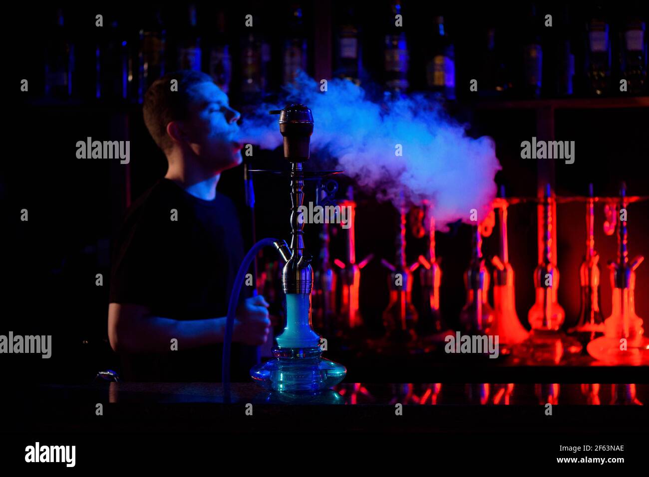 Man smoking traditional hookah pipe and exhaling smoke in hookah cafe ...