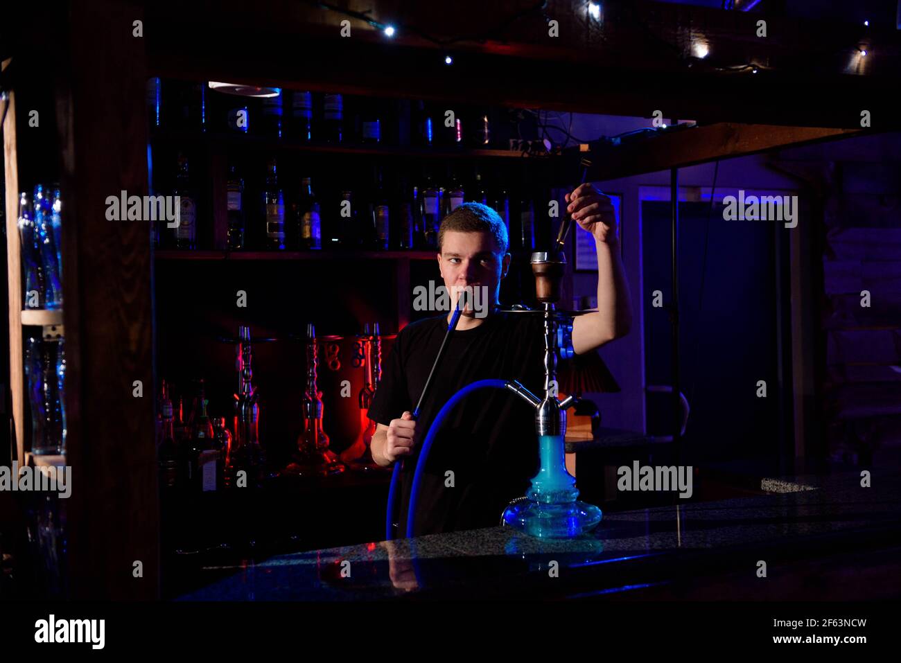 Man smoking traditional hookah pipe and exhaling smoke in hookah cafe ...