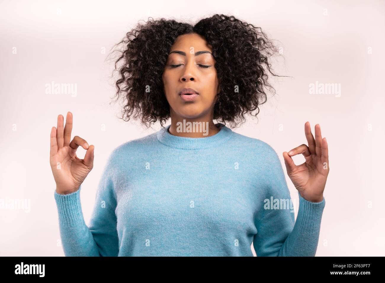 Calm african woman in blue relaxing, meditating. She calms down ...