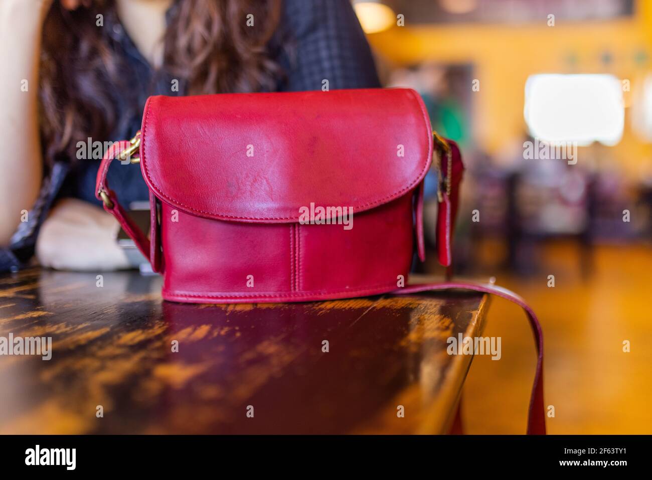 Red handbag on vintage-looking restaurant table with blurry background ...