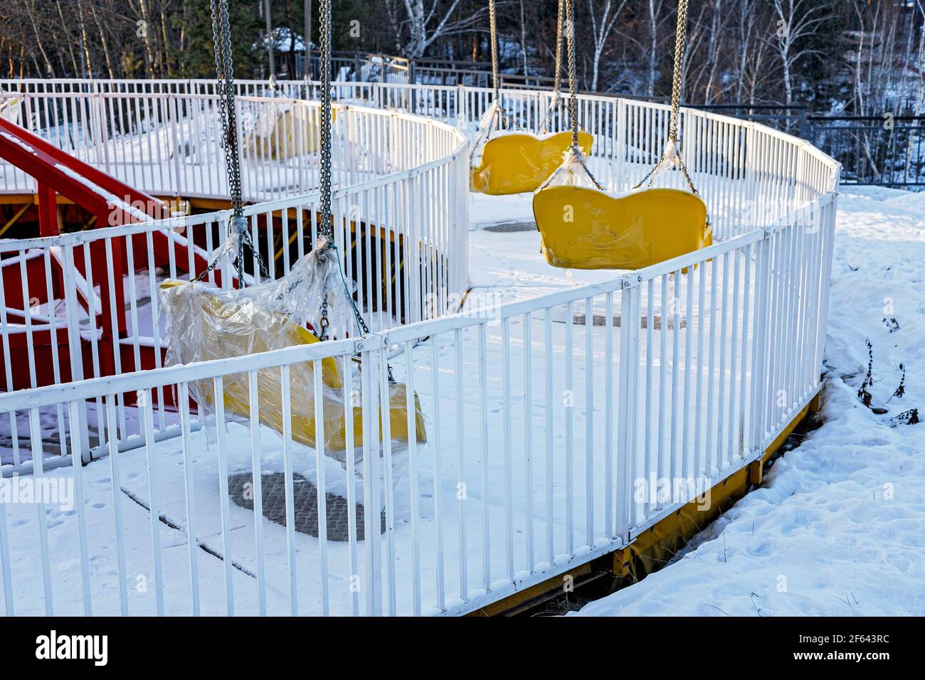 Swinging ride yellow seats covered with snow. Winter amusement park ...
