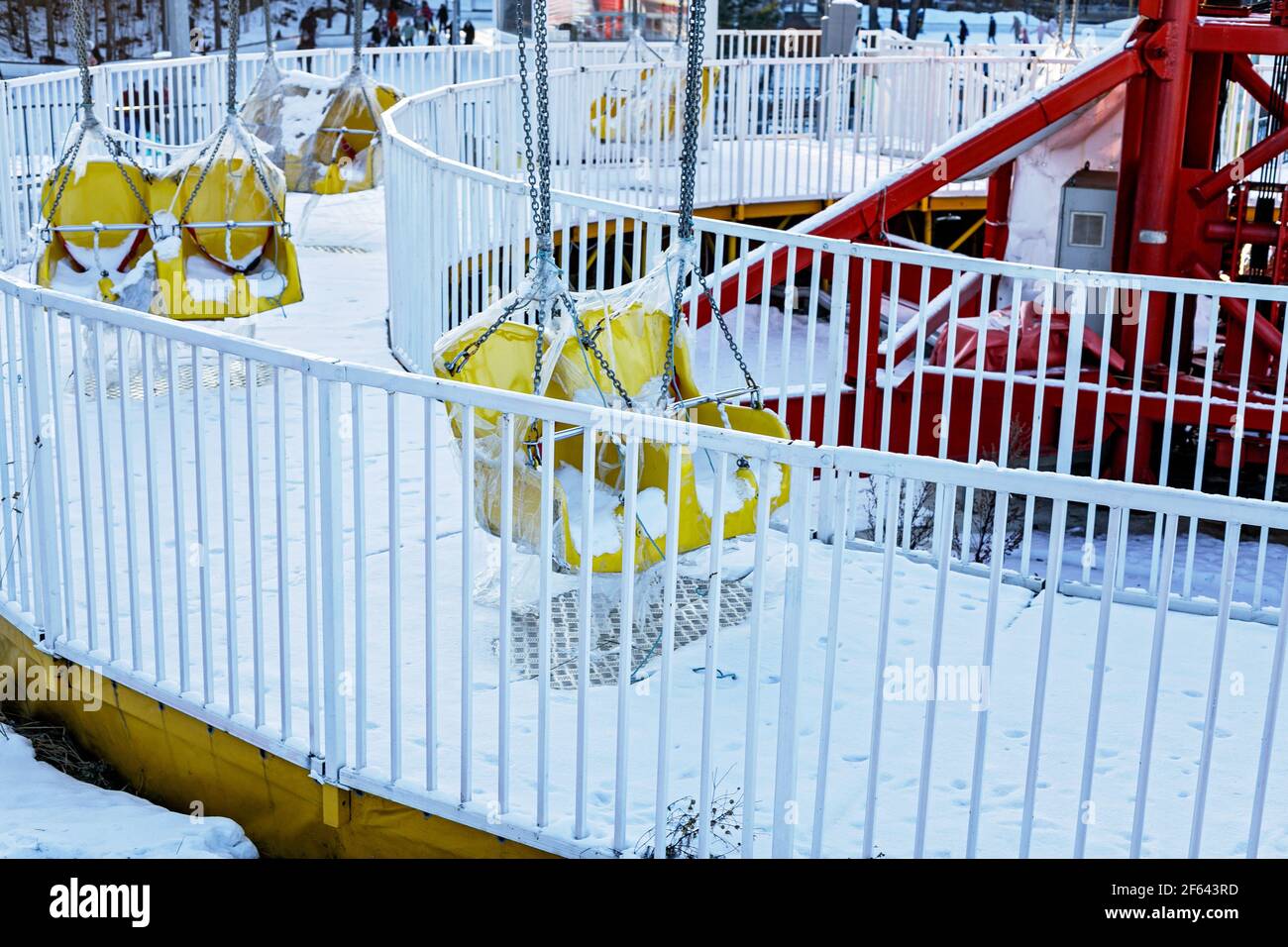 Swinging ride yellow seats covered with snow. Winter amusement park ...