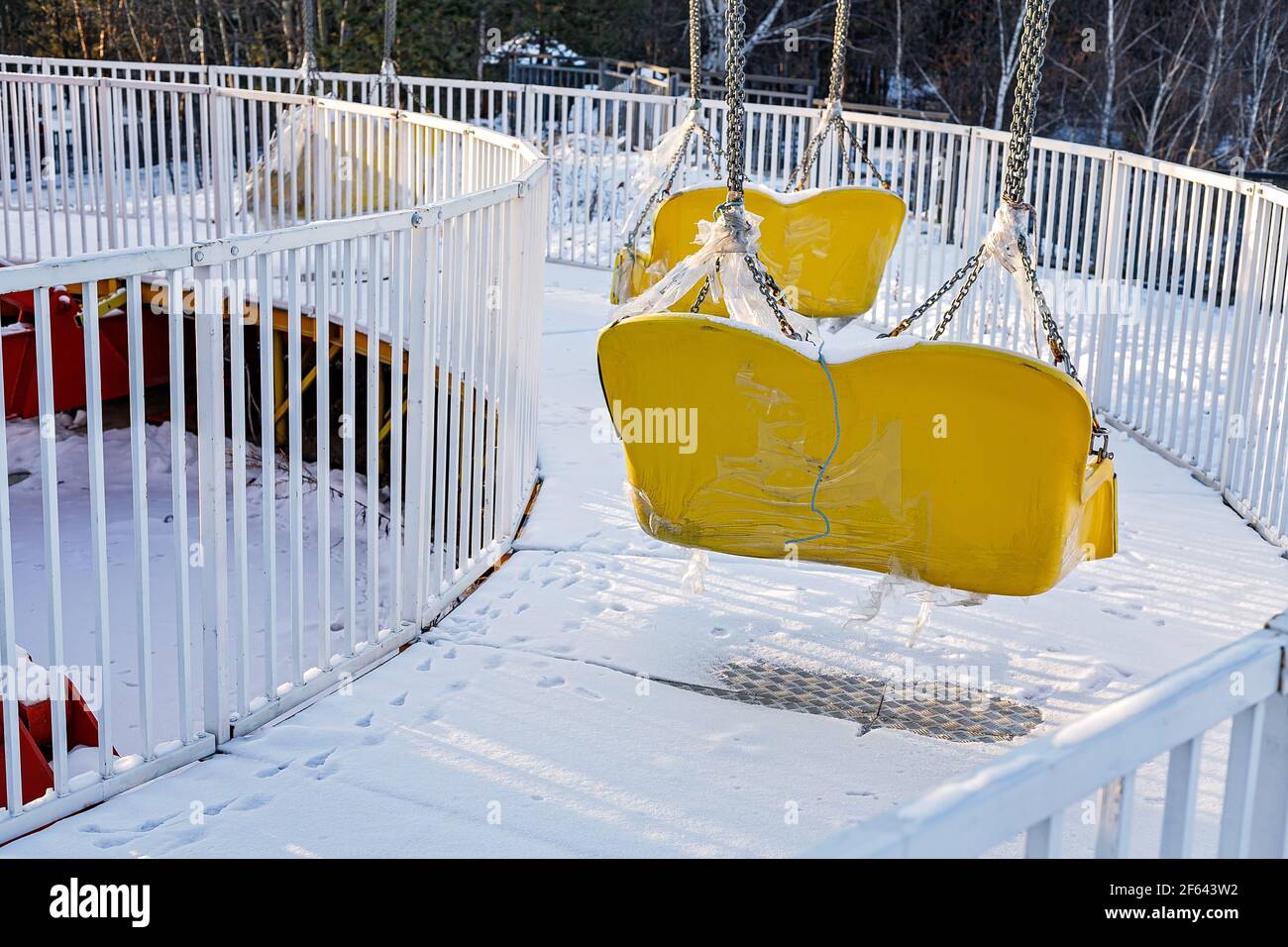 Swinging ride yellow seats covered with snow. Winter amusement park ...