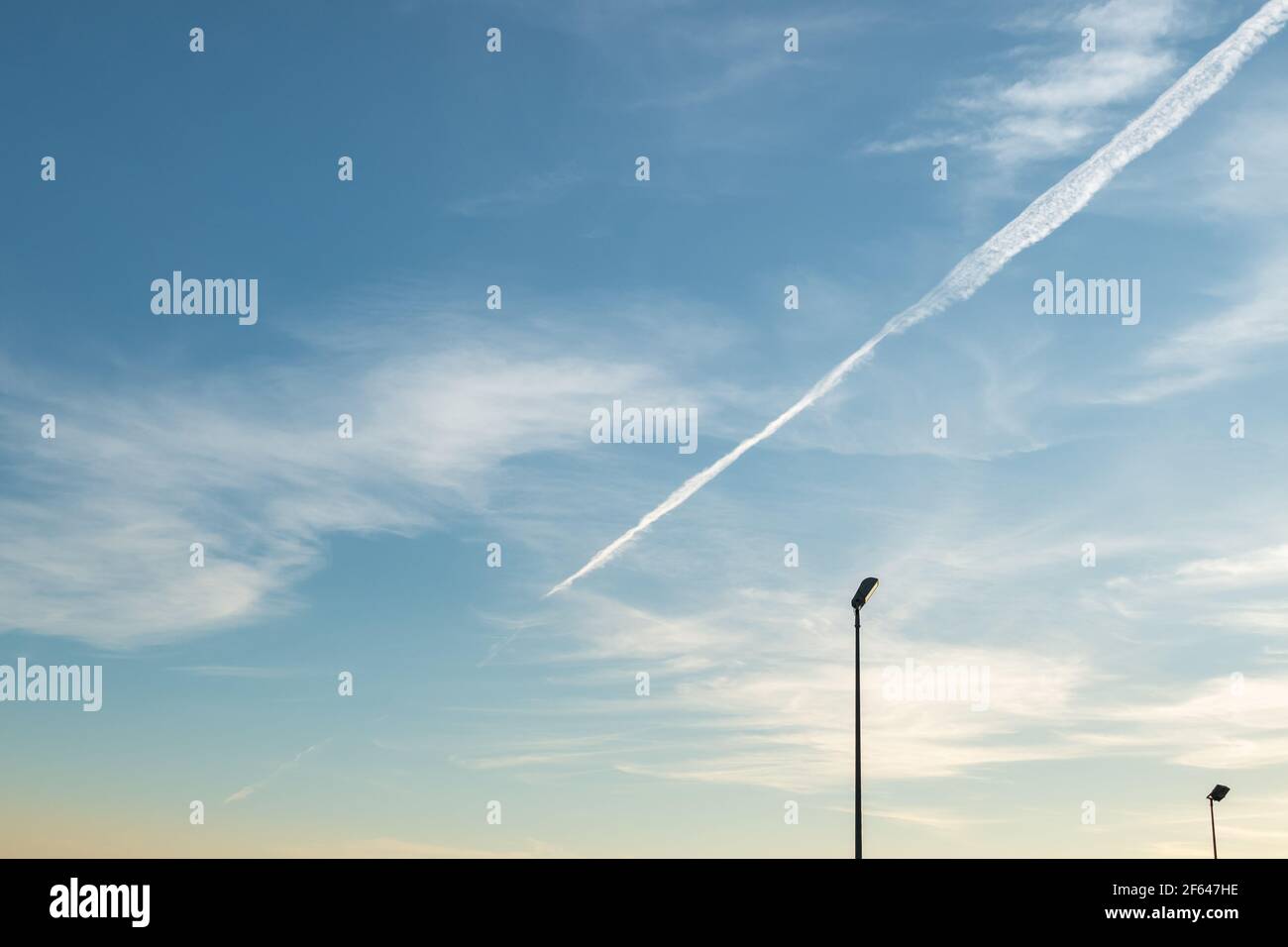 blue sky with airplane trace and silhouette of two streetlights Stock ...