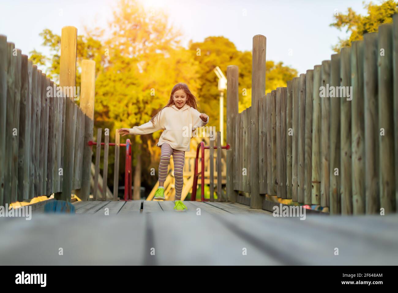 blonde child girl running on wooden bridge with sunlight Stock Photo ...