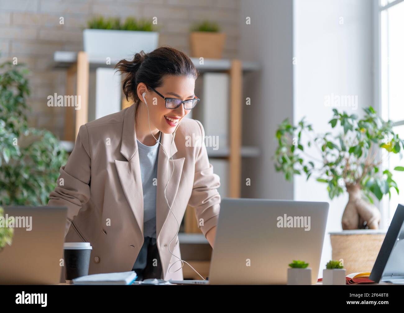 Happy casual beautiful woman working on a laptop, talking with somebody ...