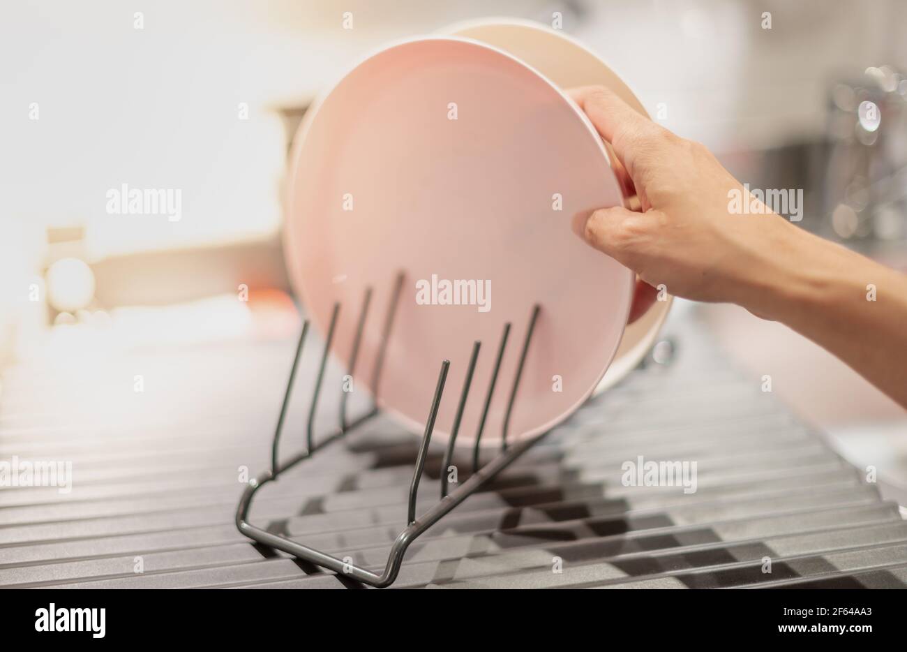 Female hand of woman putting just washed clean plate in the stainless ...